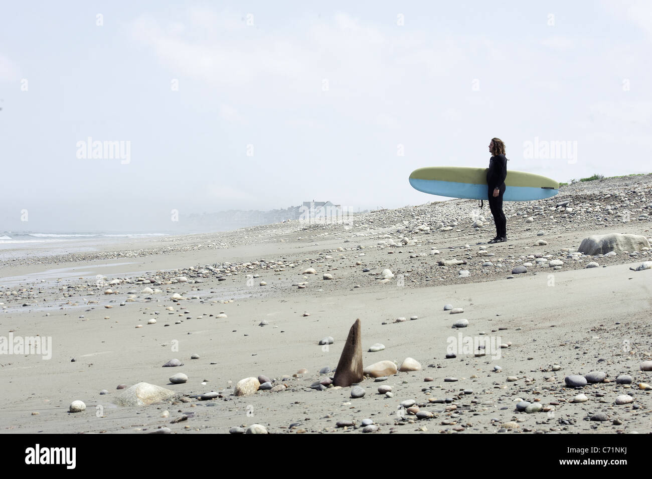 A man with a surfboard checks out the surf Stock Photo - Alamy
