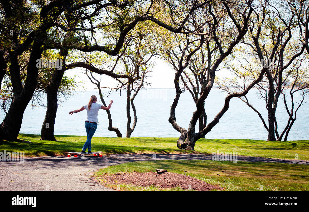 A blonde woman longboards with a beach in the background Stock Photo ...