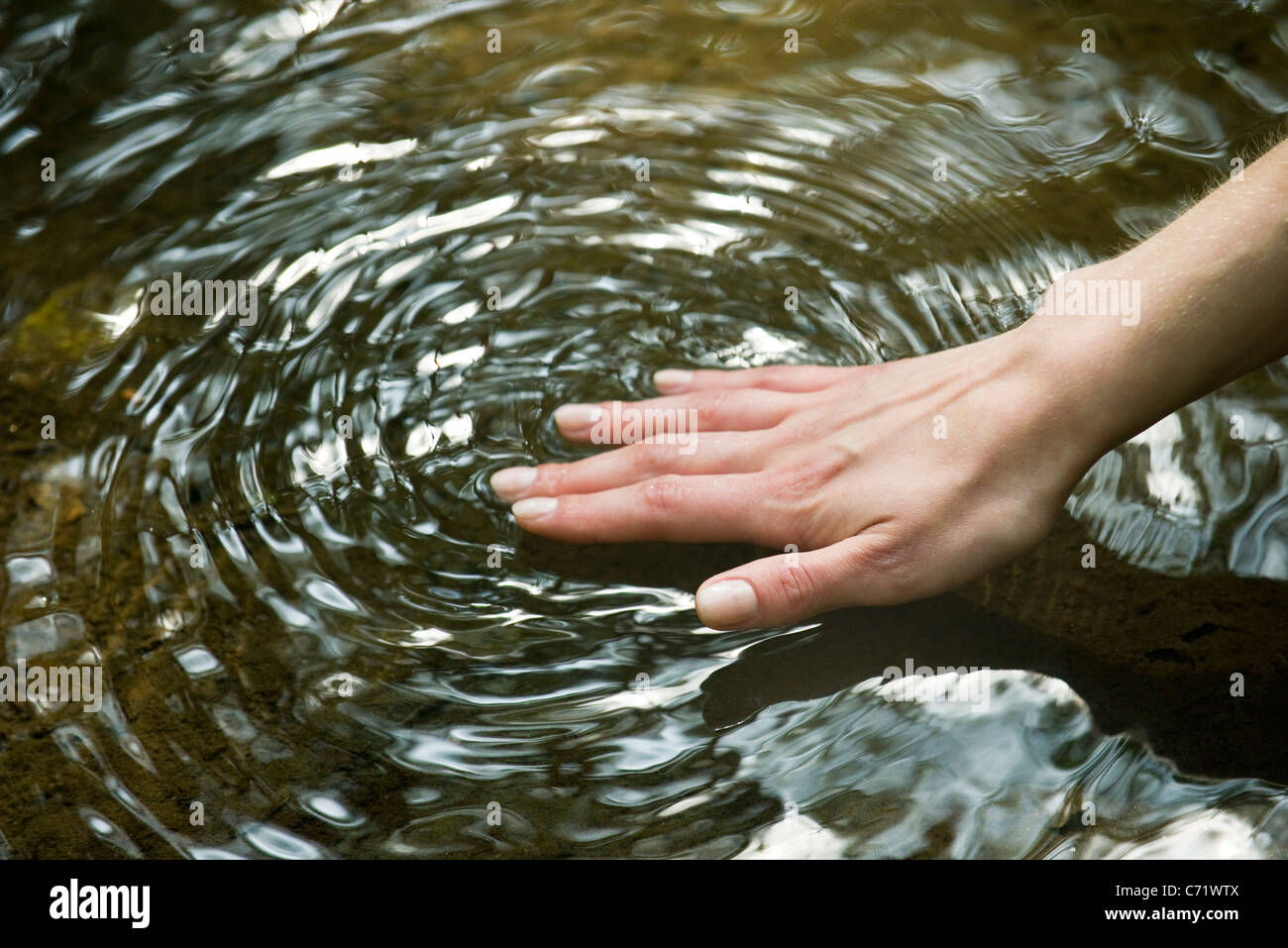 Woman's hand touching surface of water Stock Photo - Alamy