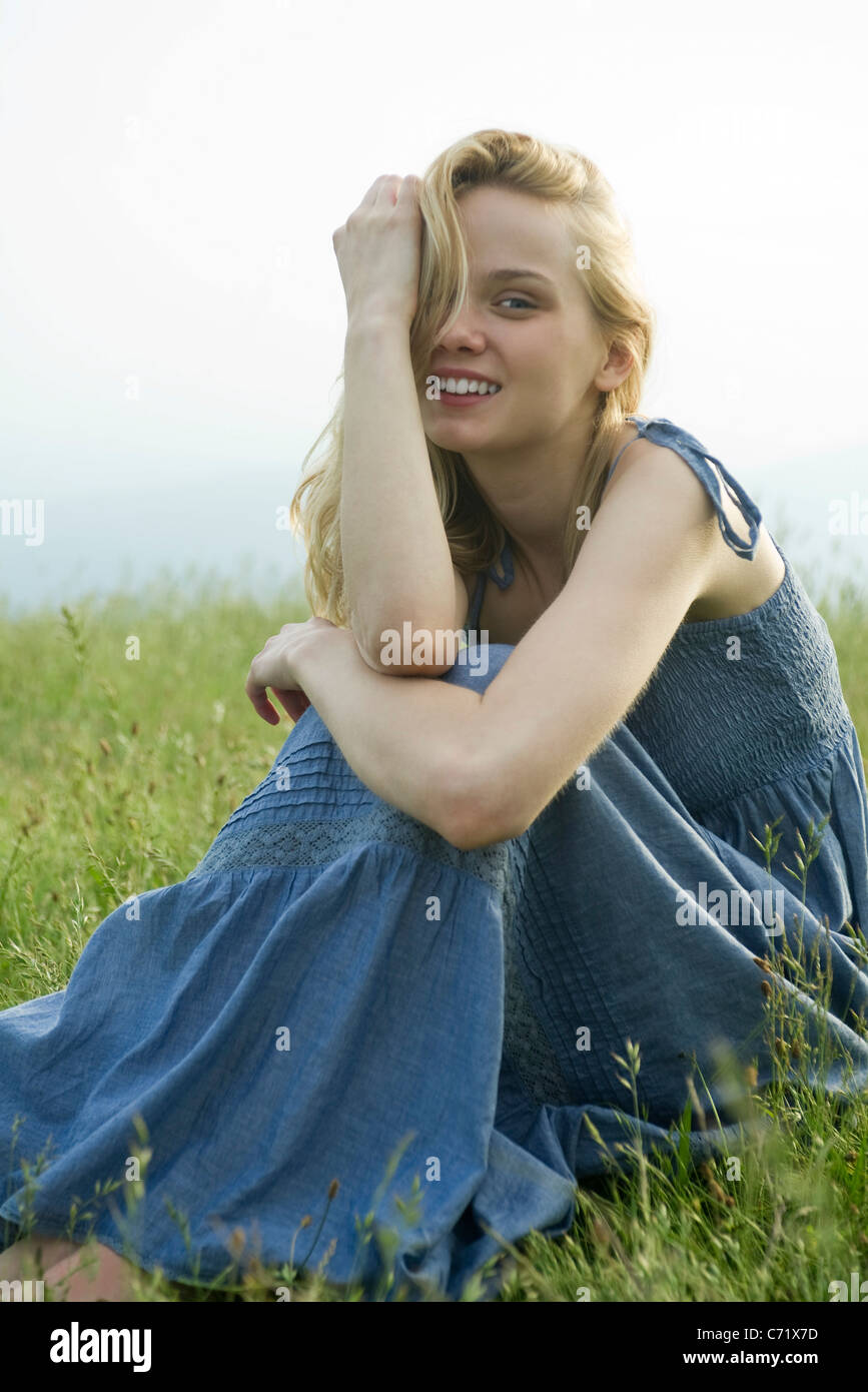 Young woman sitting in field of grass, portrait Stock Photo - Alamy