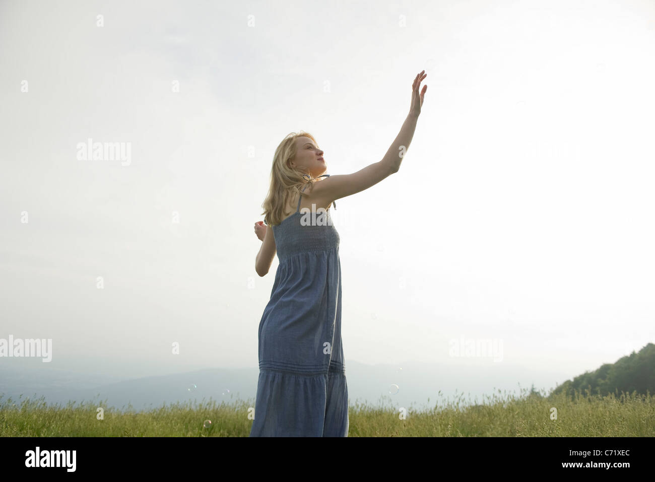 Young woman reaching to touch bubble floating above her head Stock ...