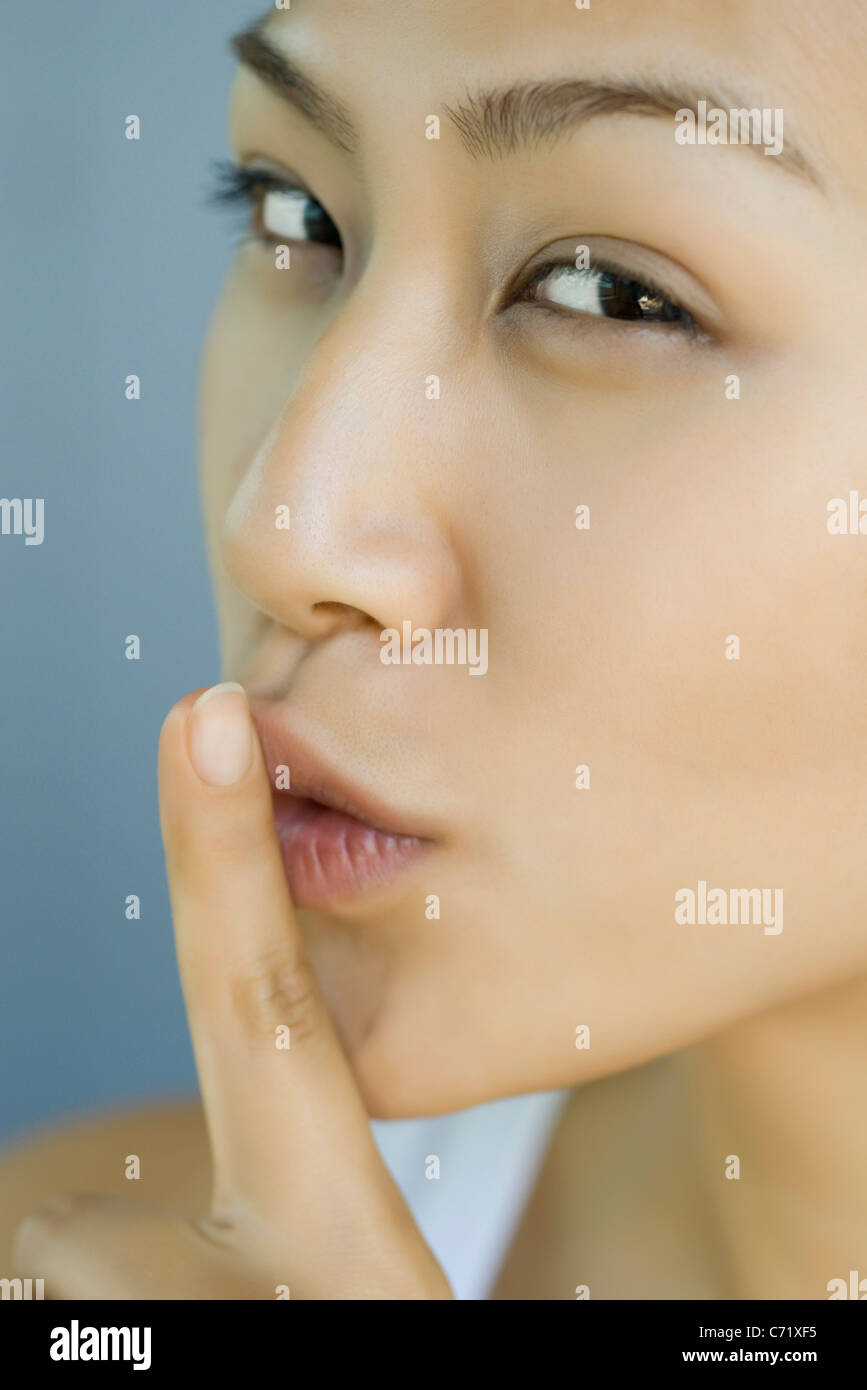 Woman holding finger against lips, portrait Stock Photo - Alamy