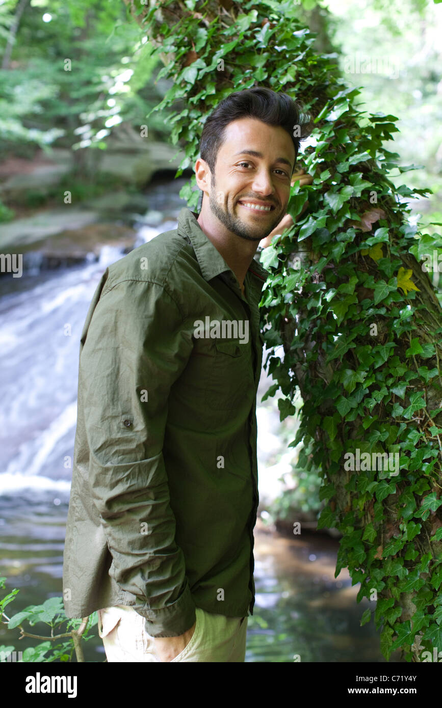 Man standing beside ivy covered tree, portrait Stock Photo - Alamy