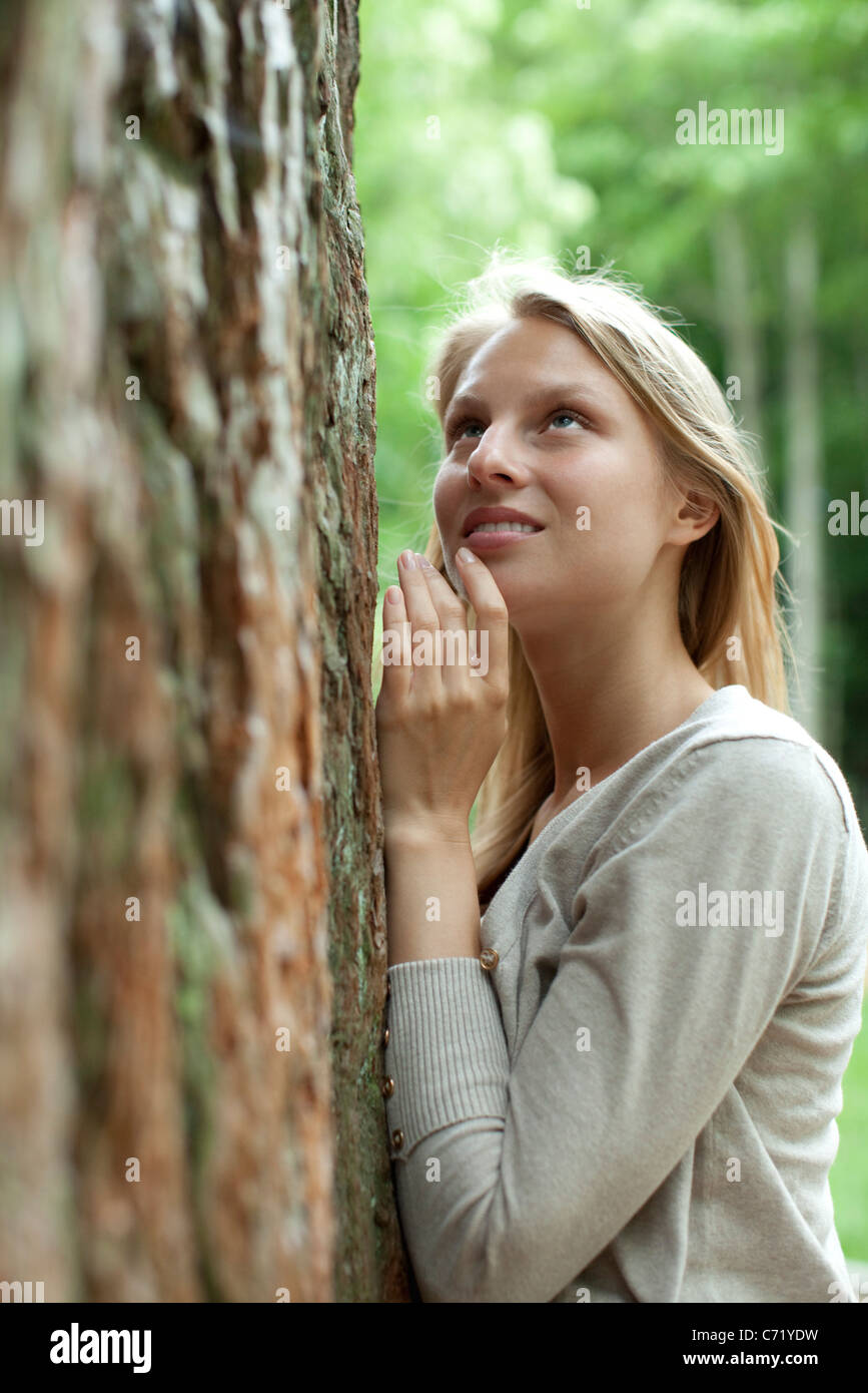 Woman leaning against tree, looking up Stock Photo - Alamy