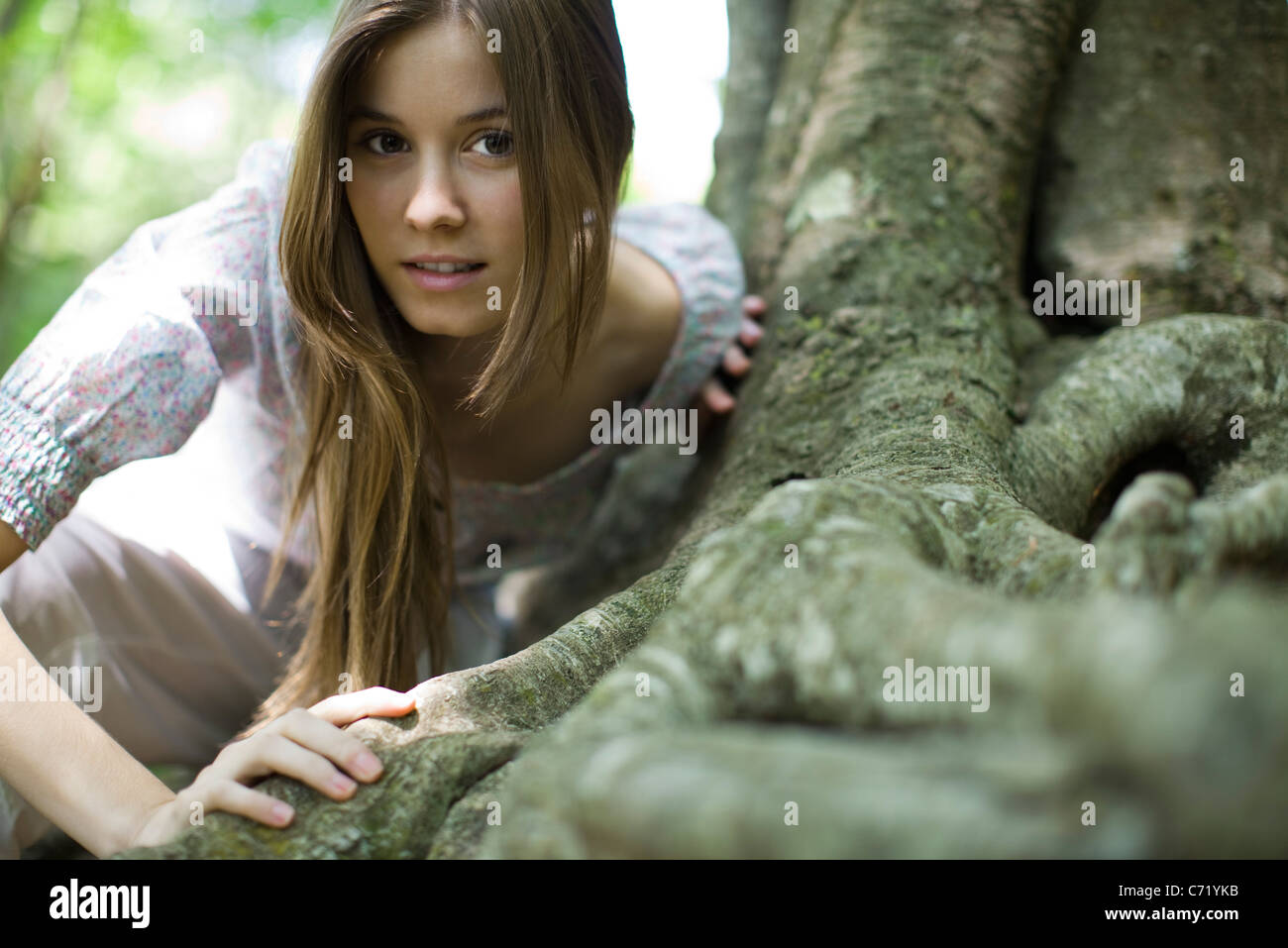 Young woman leaning on roots of tree Stock Photo - Alamy