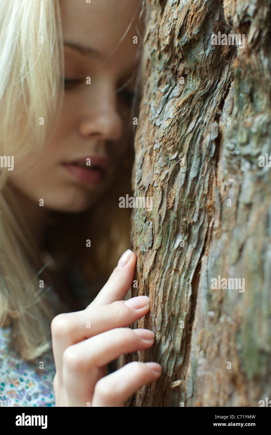 Young woman touching tree trunk Stock Photo - Alamy