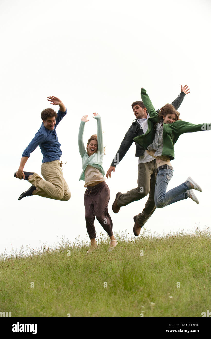 Young adults jumping on meadow Stock Photo - Alamy