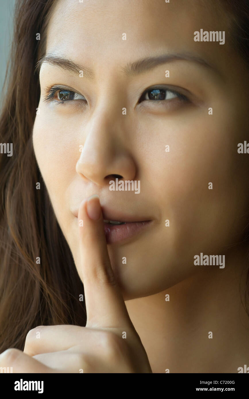 Young woman with finger on lips Stock Photo - Alamy