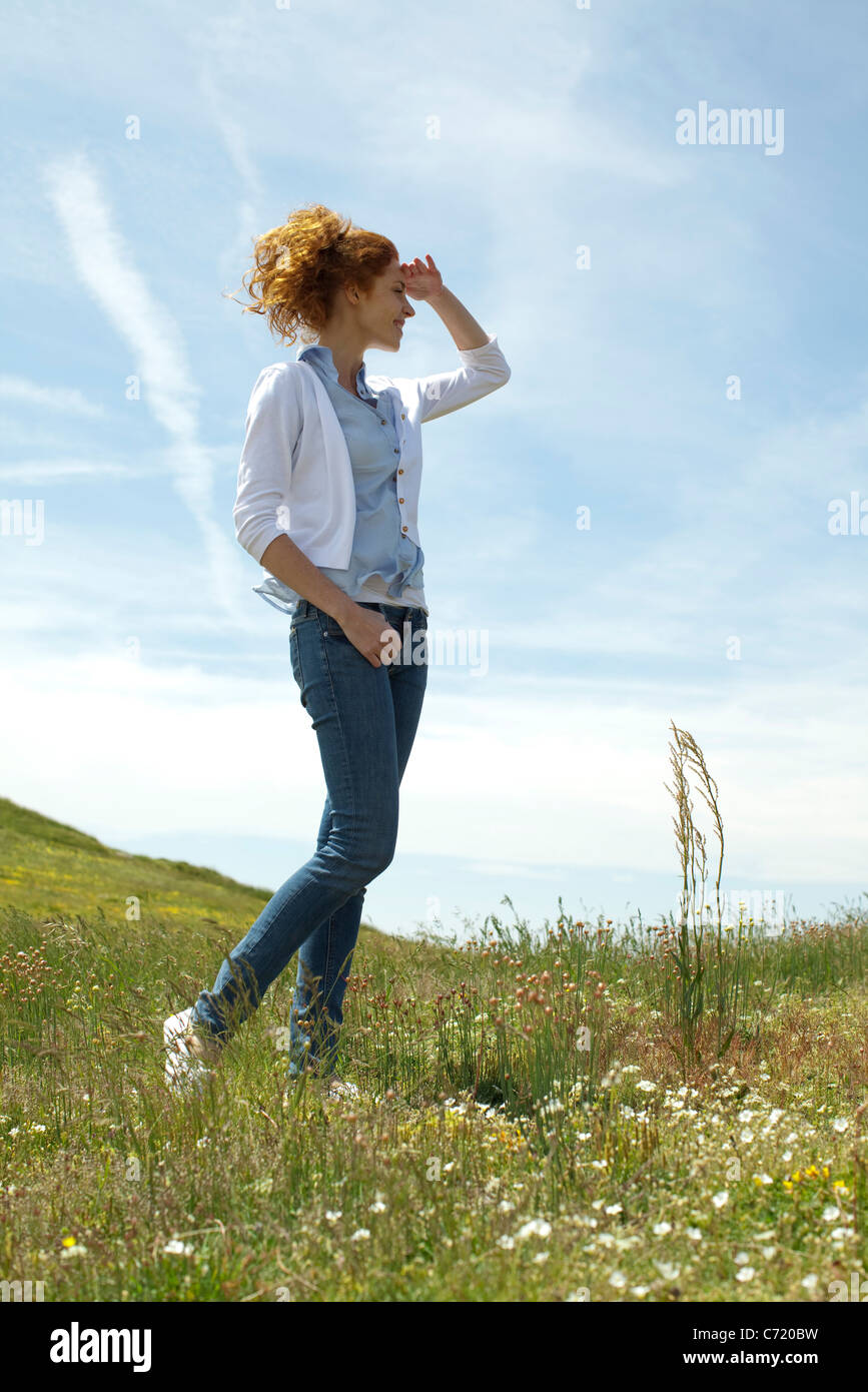 Woman walking in meadow, shading eyes with hand Stock Photo - Alamy