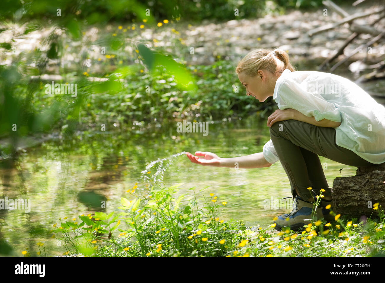 Young woman splashing water by river Stock Photo - Alamy