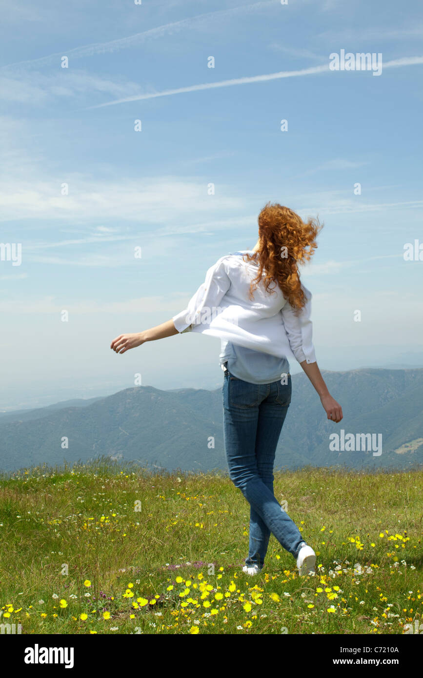 Woman walking through meadow with arms outstretched Stock Photo - Alamy