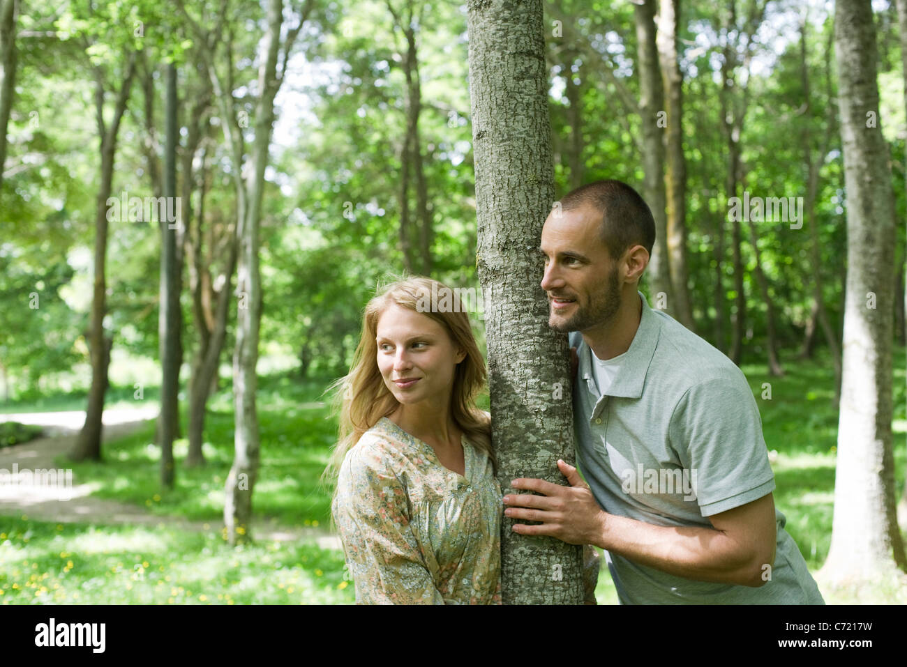 Couple leaning against tree trunk Stock Photo - Alamy
