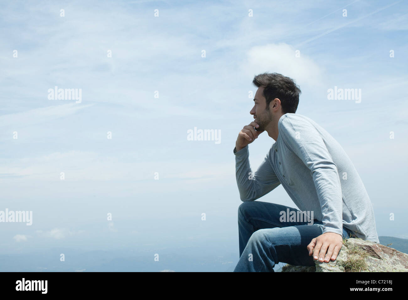Man sitting on rock, contemplating view Stock Photo - Alamy