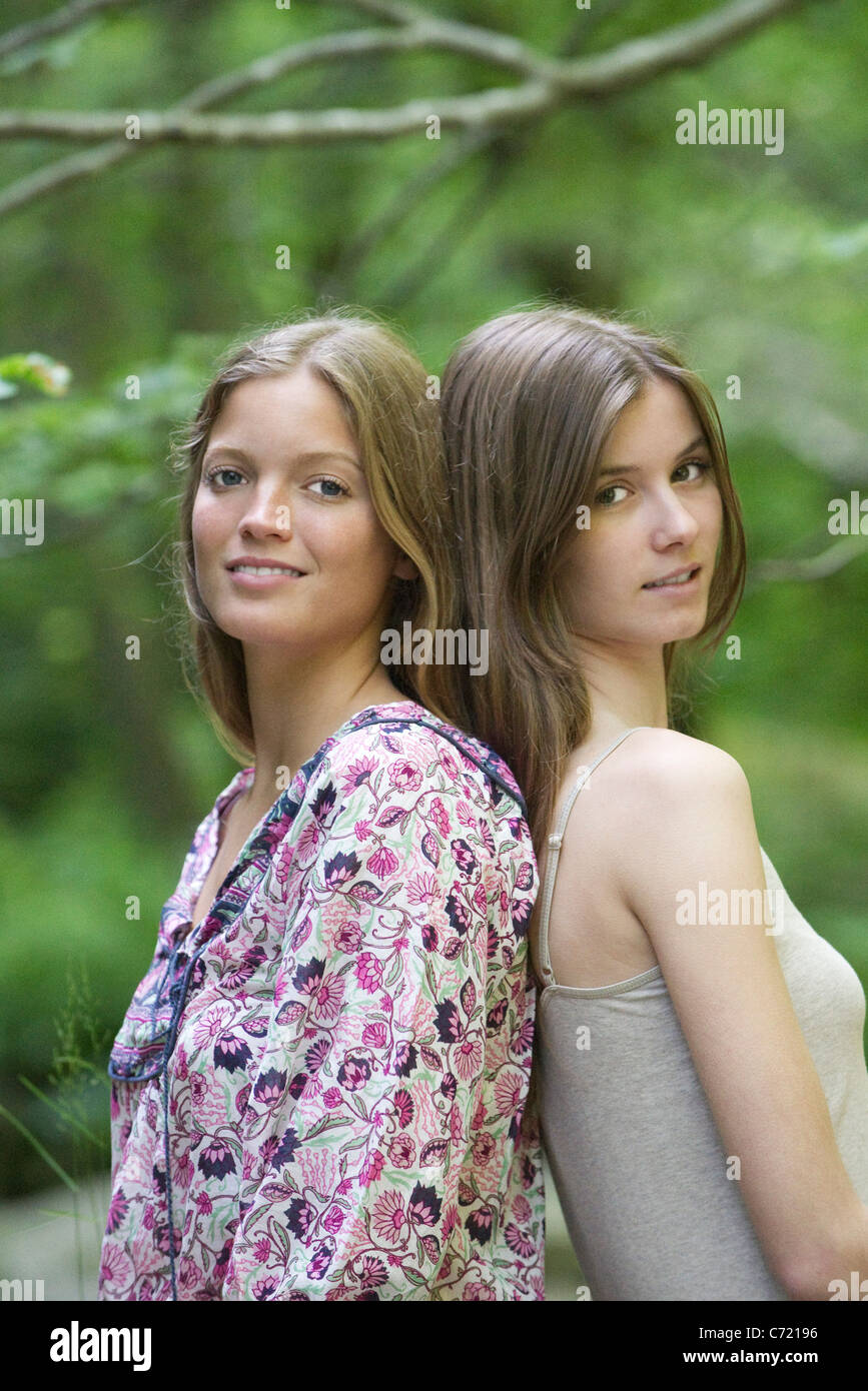 Female friends back to back, portrait Stock Photo - Alamy