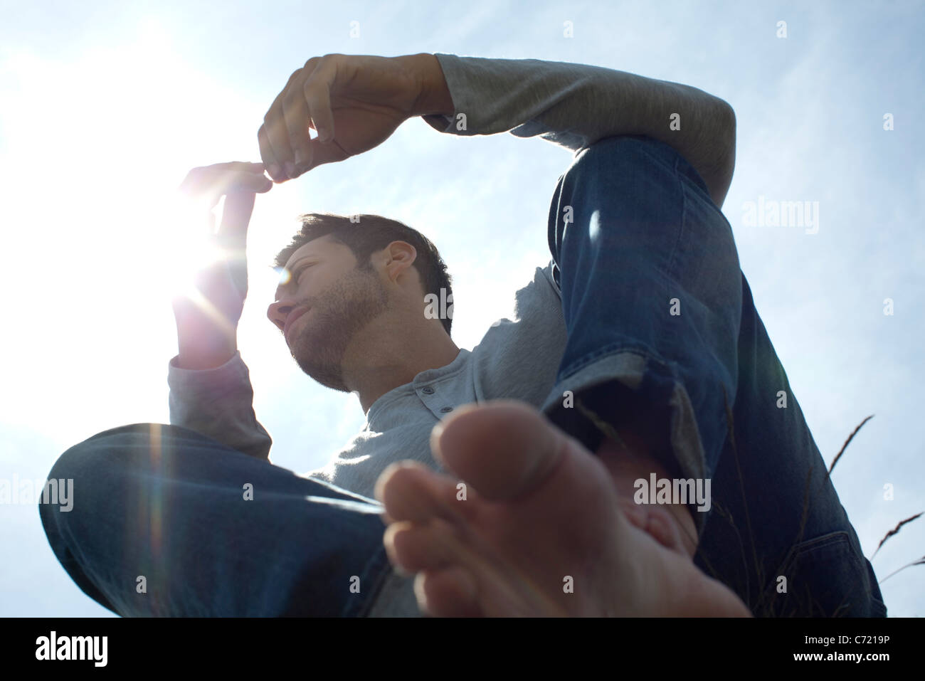 Man relaxing outdoors, backlit by sun, low angle view Stock Photo - Alamy