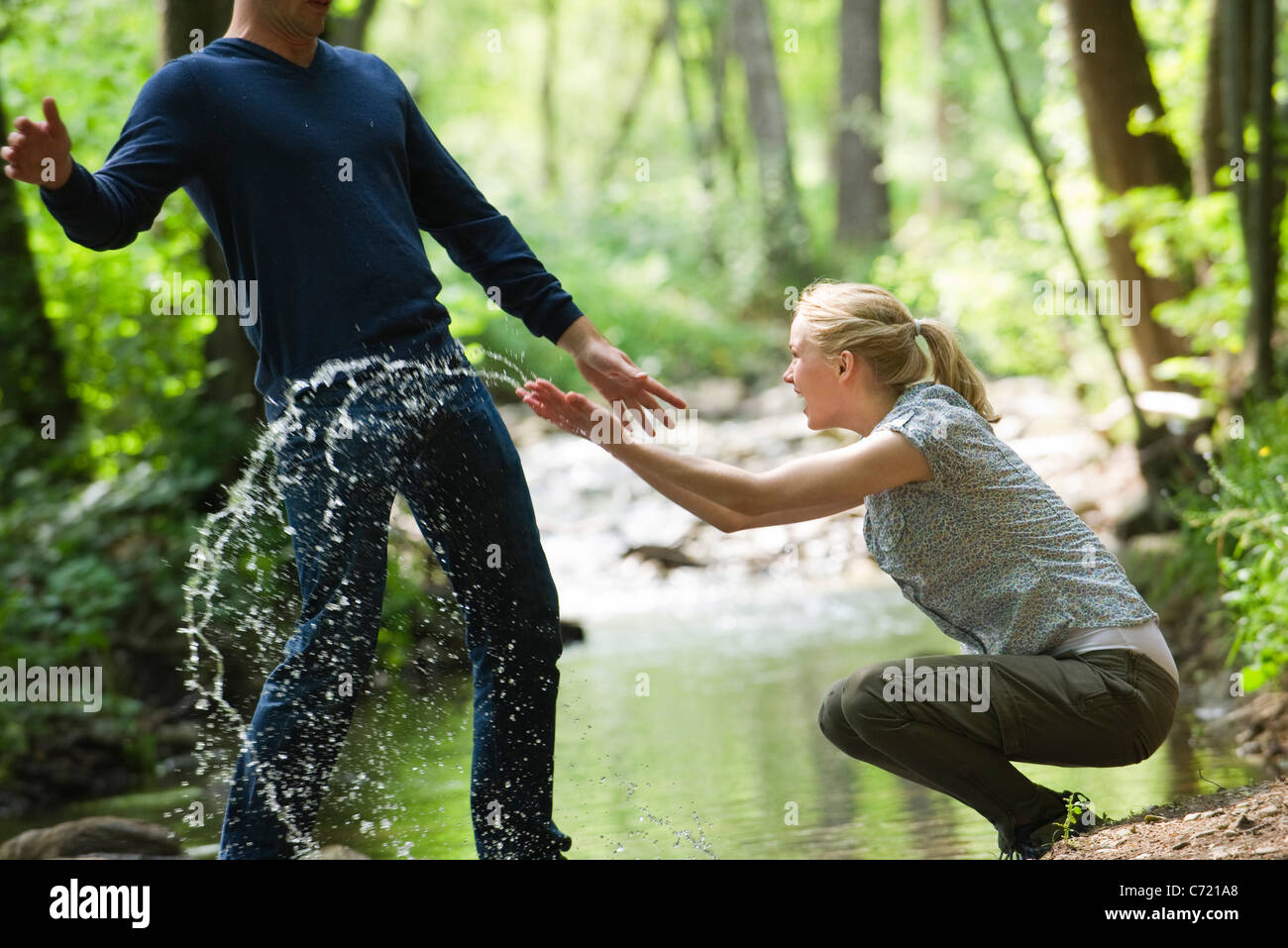 Young woman splashing water at man Stock Photo - Alamy
