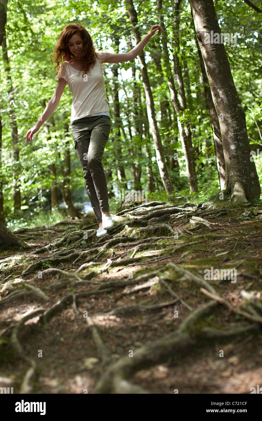 Woman walking on tree roots in woods Stock Photo - Alamy