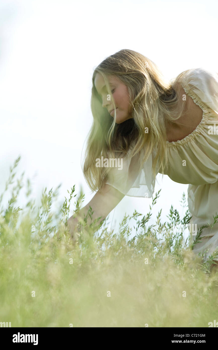 Young woman bending over tall grass Stock Photo - Alamy