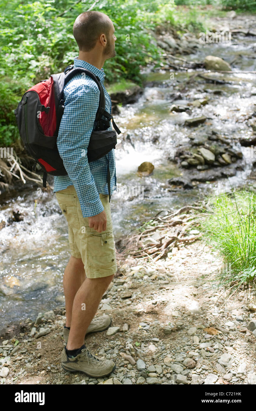 Man hiking along stream in woods Stock Photo - Alamy