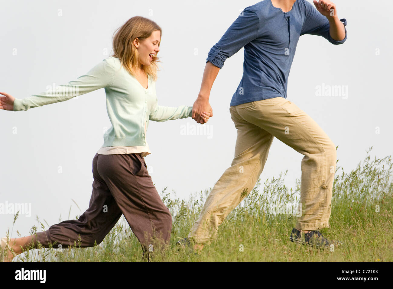 Young woman running on meadow with boyfriend Stock Photo - Alamy