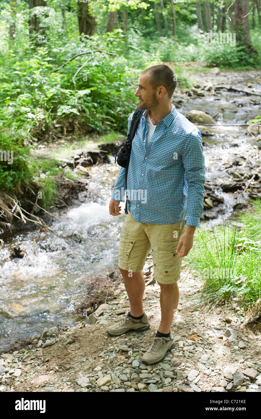 Man hiking along stream in woods Stock Photo - Alamy