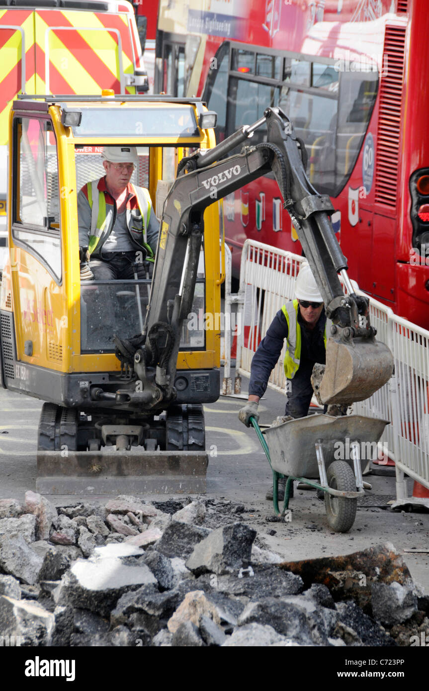 Aerial view workers & mini excavator working on road works in bus lane ...