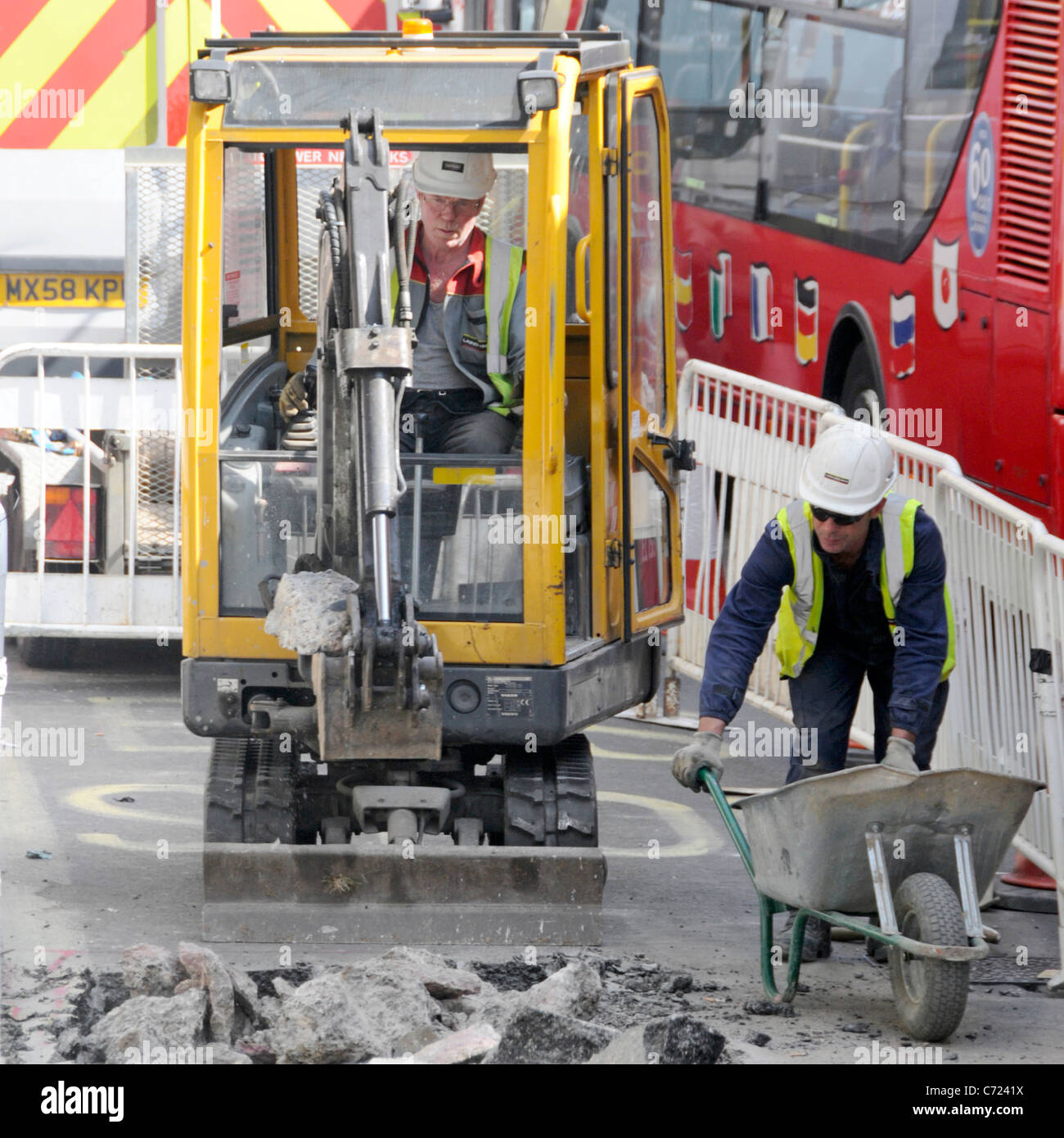 Aerial view workers & mini excavator working on road works in bus lane ...