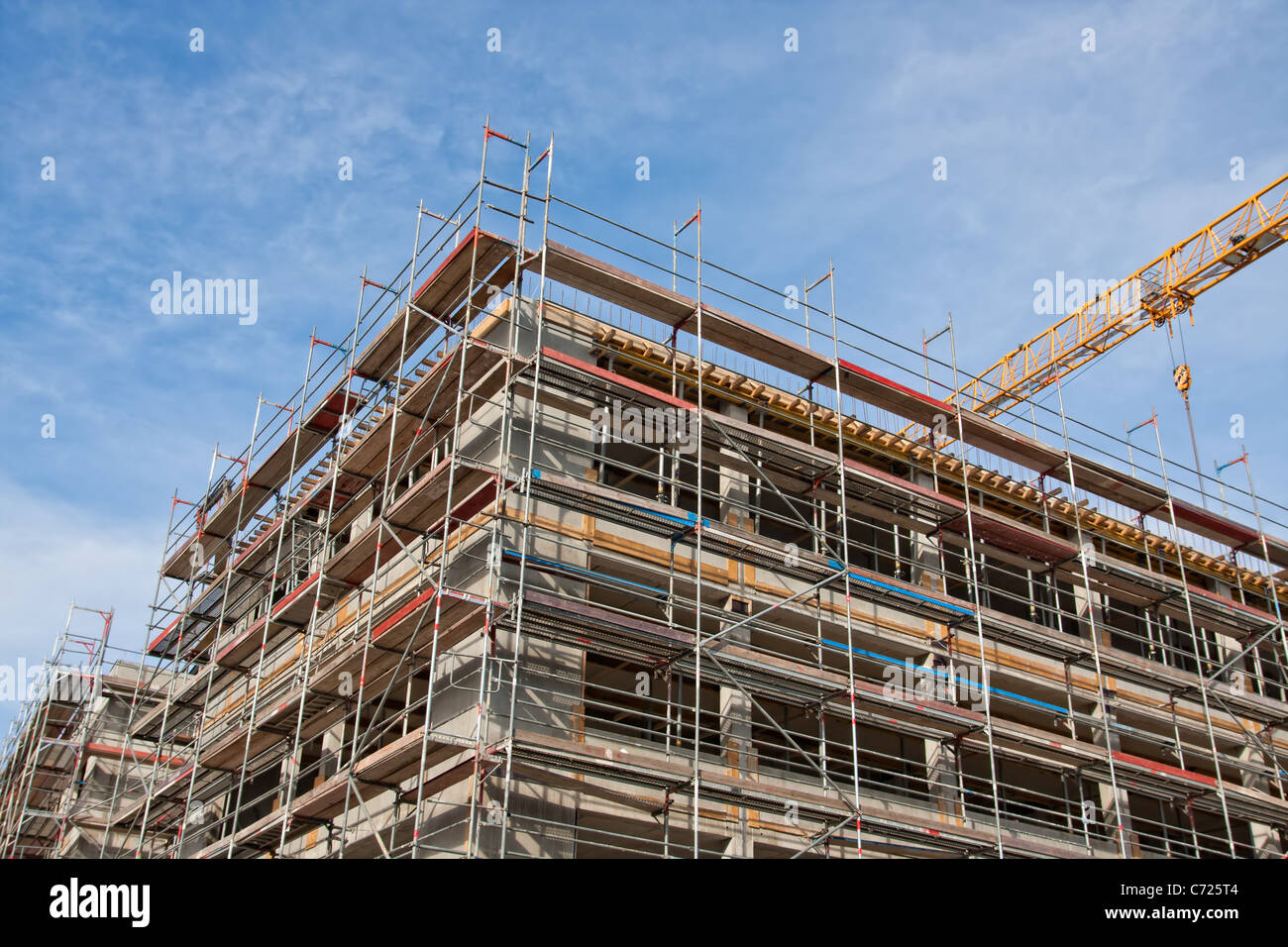 Large construction site with scaffolding building, yellow tower crane ...