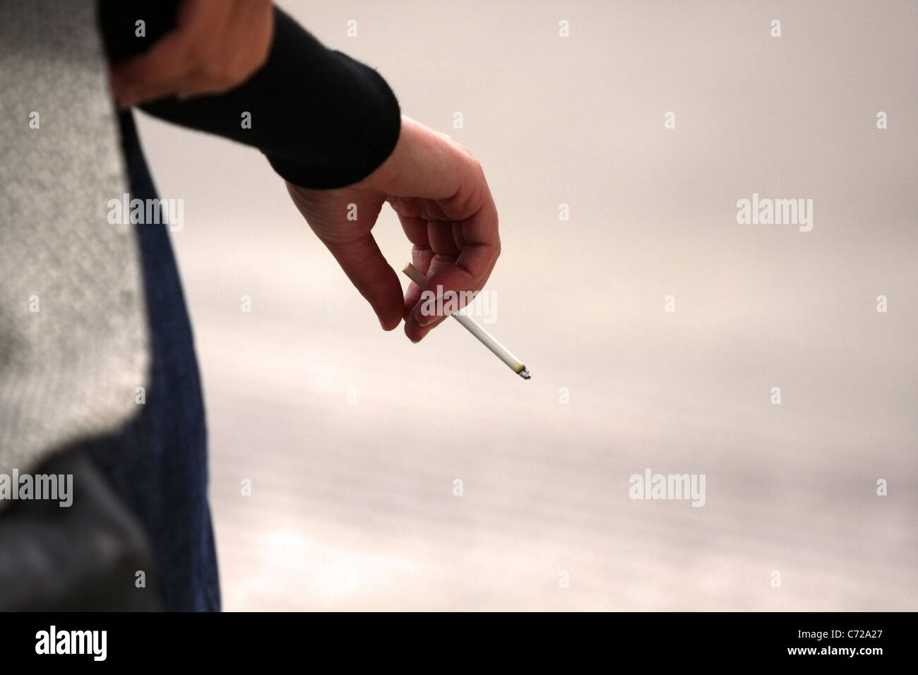 A hand holding a lighted cigarette Stock Photo - Alamy