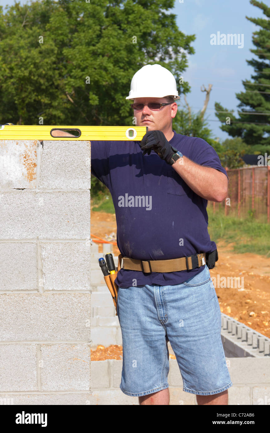 Supervisor checking cinder block building walls for level Stock Photo ...