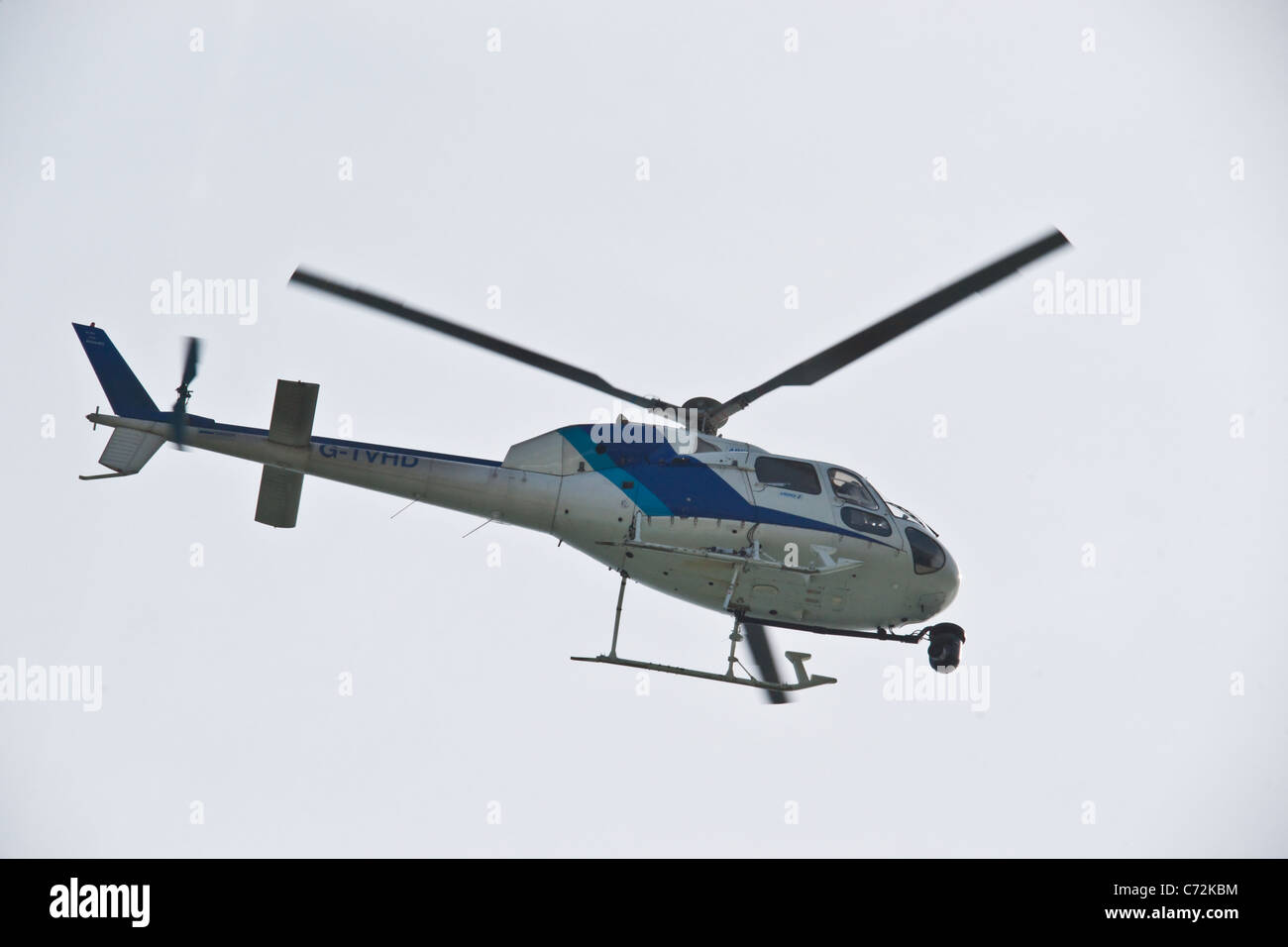 A helicopter in flight with a TV camera attached below the cockpit nose ...
