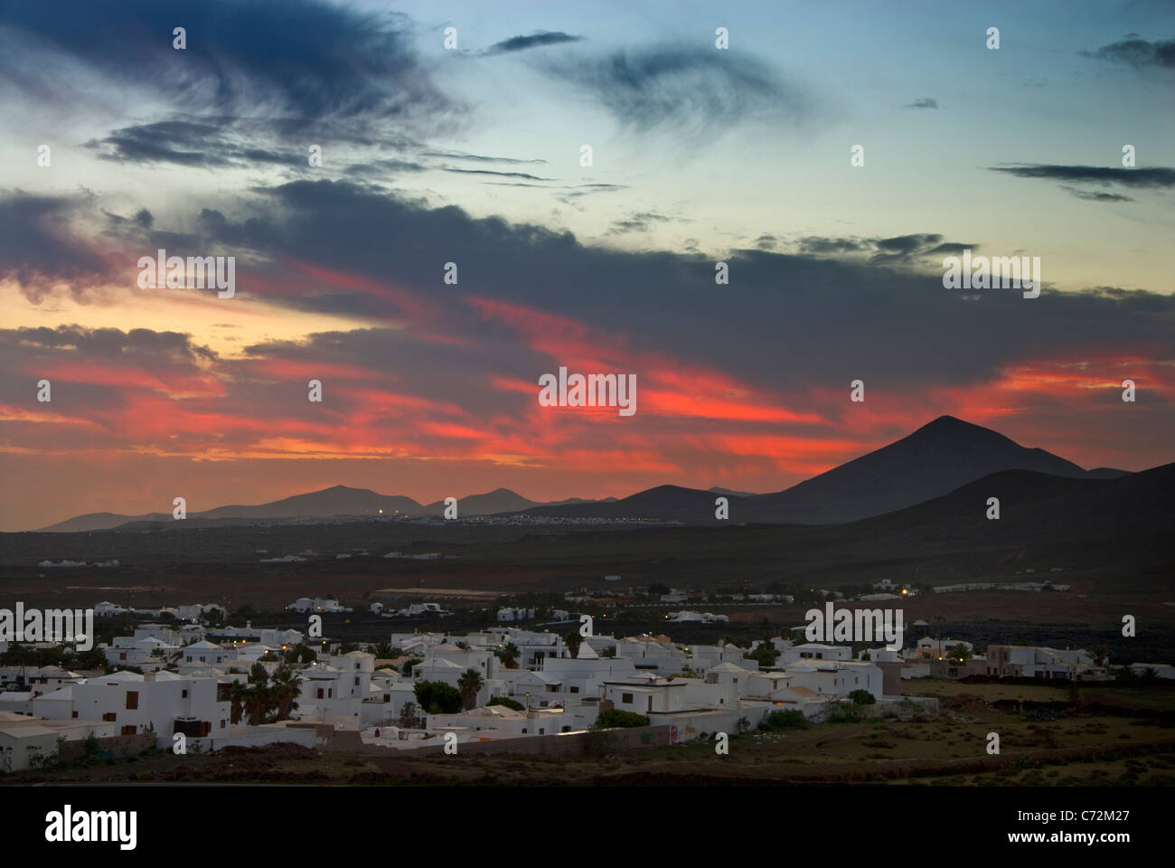 TAHICHE Fiery red sun setting behind volcano with village of Tahiche in ...