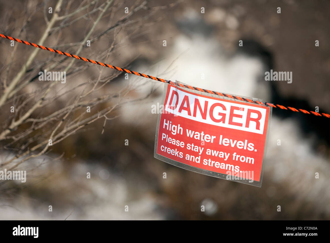Danger sign along dangerous flood water in stream, creek and river ...