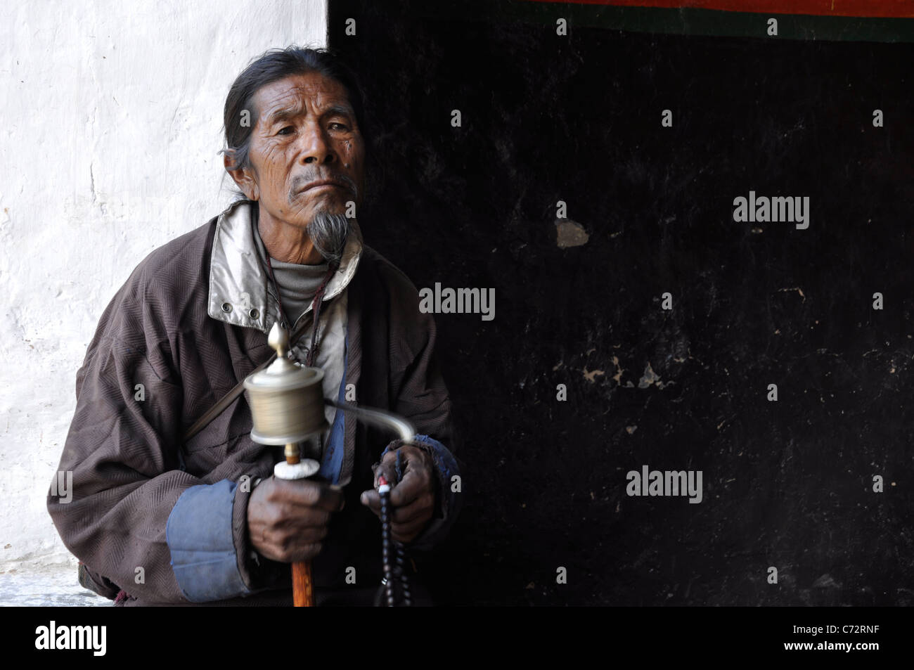 A old Buddhist follower praying outside the Yalbang monastery, Humla ...