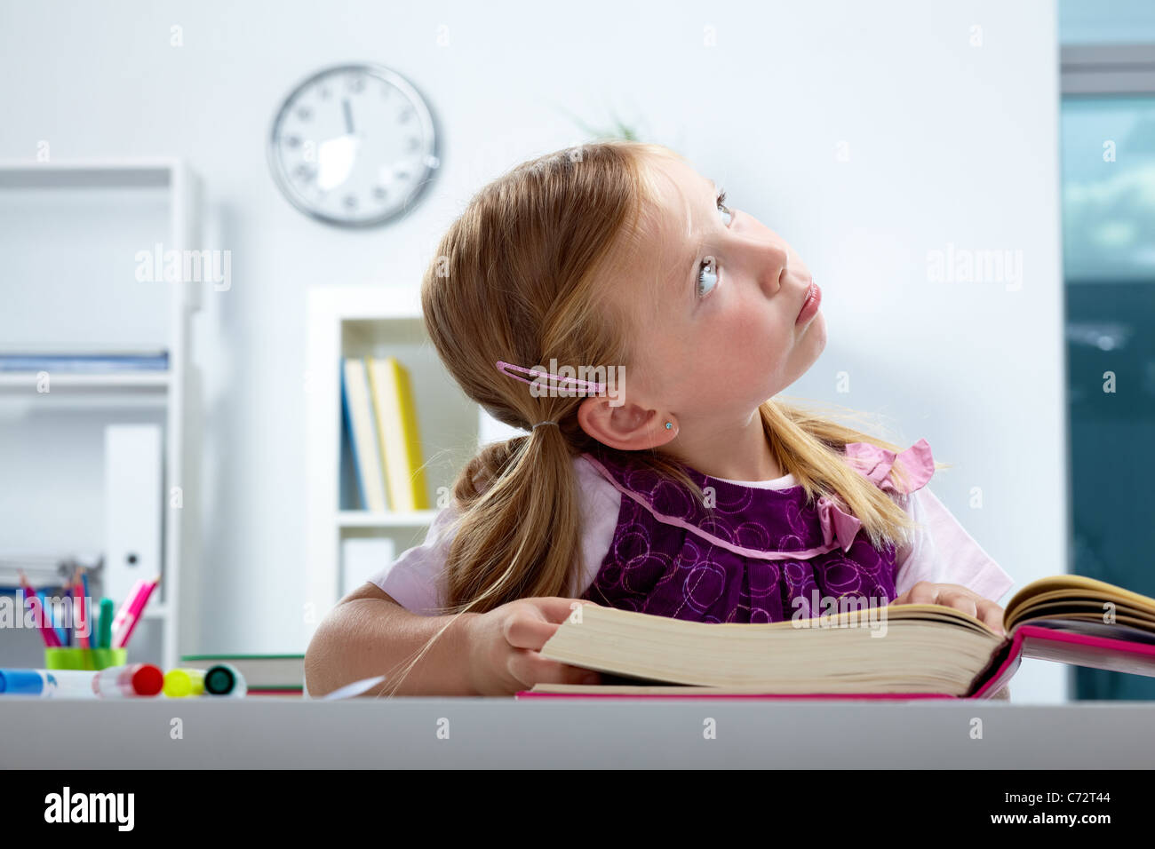 Portrait of lovely girl looking aside while reading book in library ...