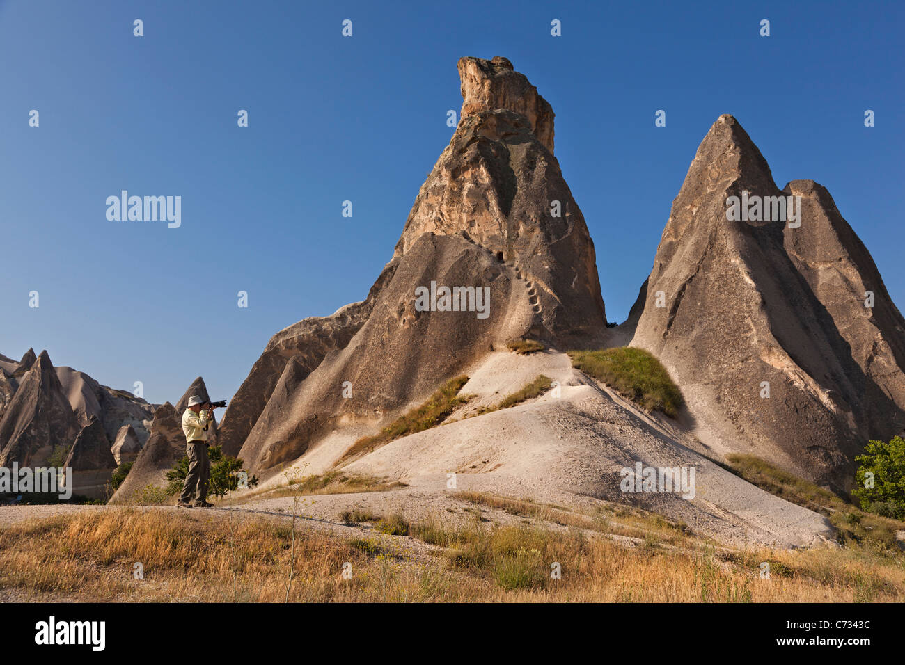A photographer in Goreme Rock Sites of Cappadocia, eroded plateau in a ...
