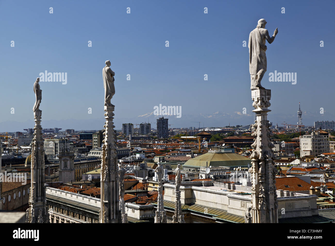 Three statues looking west a top Milan Cathedral (Duomo di Milano) roof ...