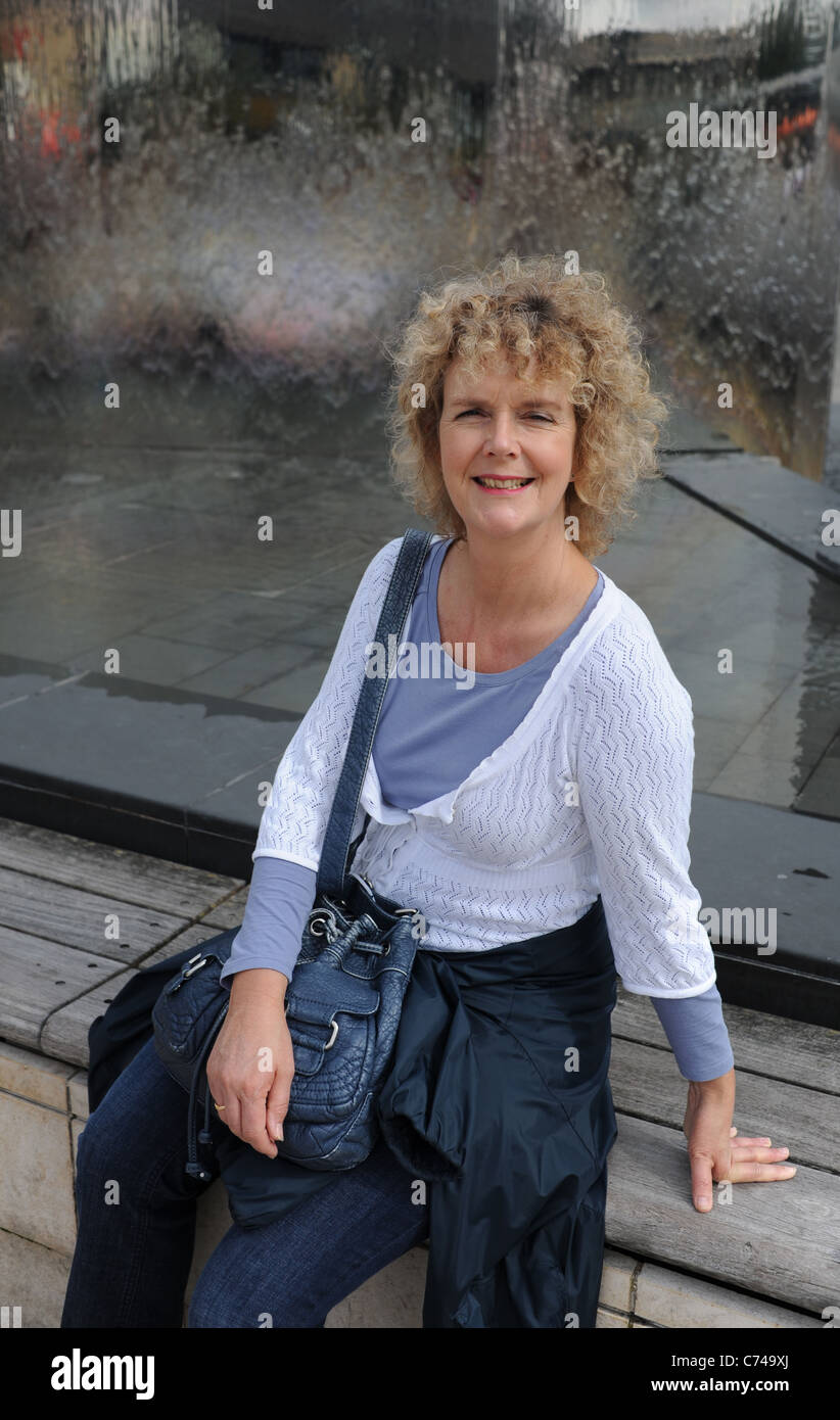 Woman sitting beside ornamental water feature in Bristol city centre UK ...