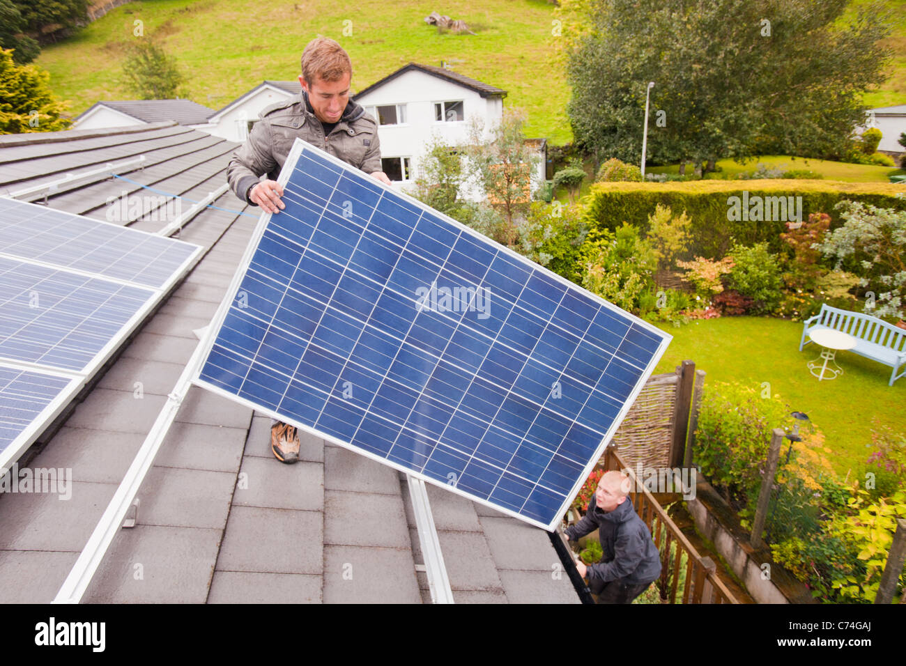 Workers installing solar electric panels on a house roof in Ambleside, UK Stock Photo - Alamy