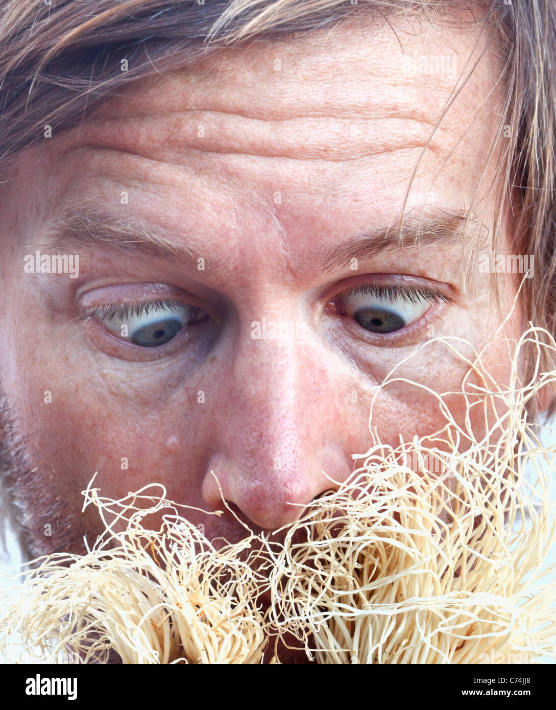 Close-up of man looking in shock at strange growth apparently growing ...