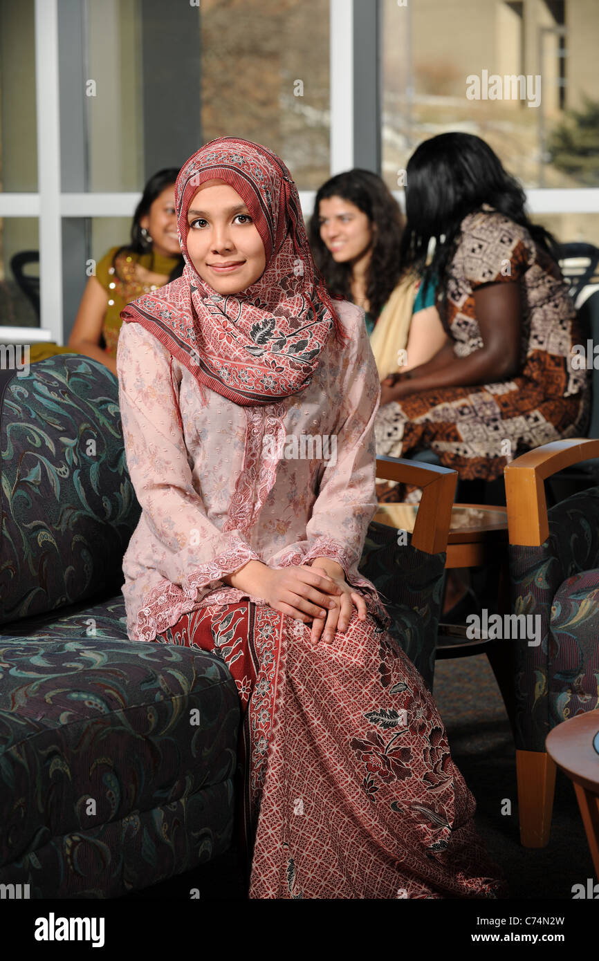 Portrait of young Muslim woman in traditional clothes with others in ...