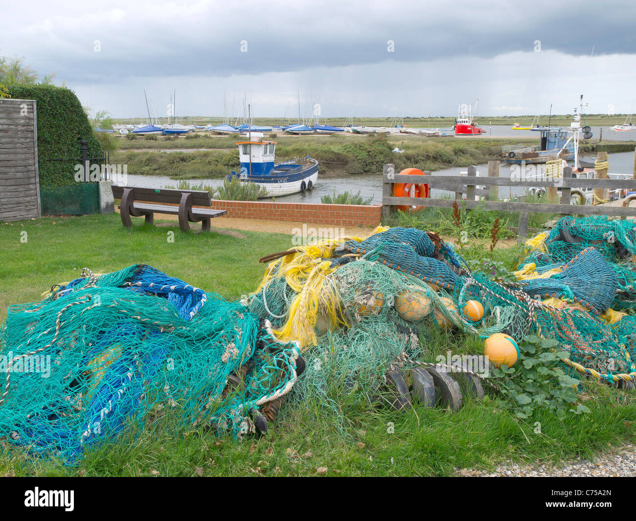 Fishing nets and floats piled in front of the harbour at Brancaster ...