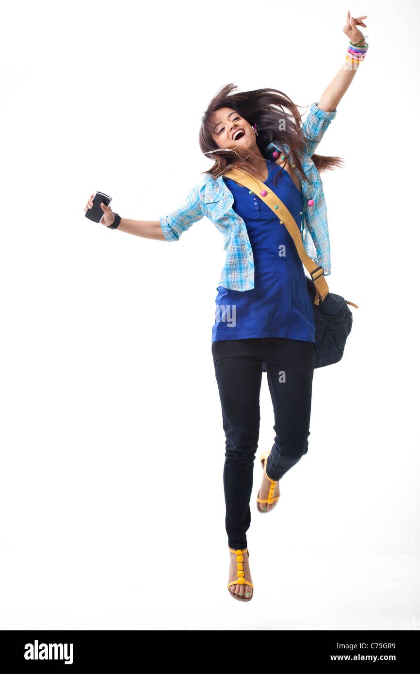 Excited female university student dancing while listening music on ...