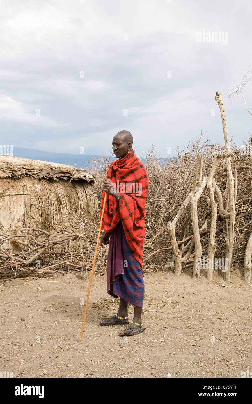 Tall Masai Maasai warrior in traditional red cloak outside a Maasai ...