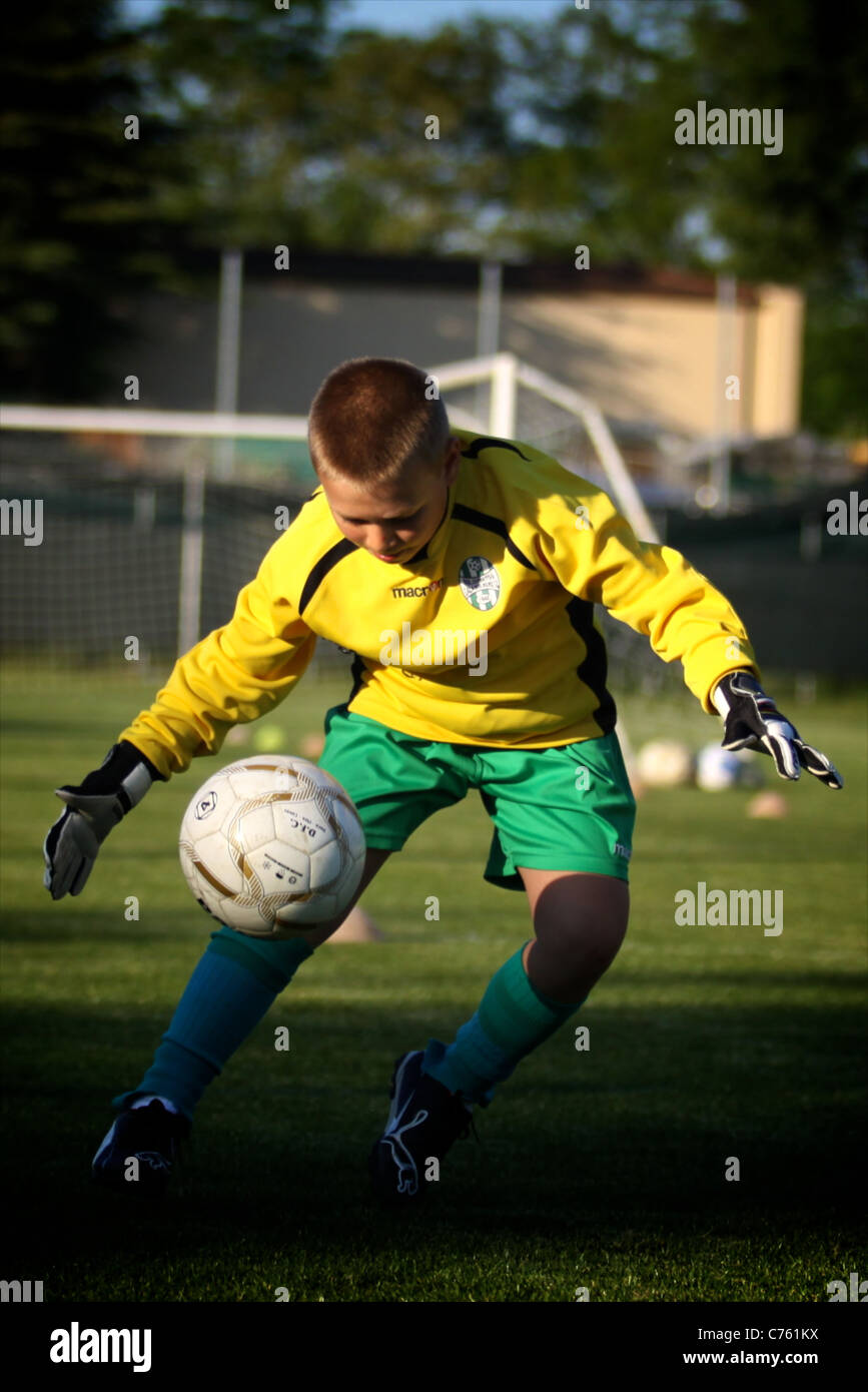 young little soccer goalkeeper is catching the ball and saving the goal ...