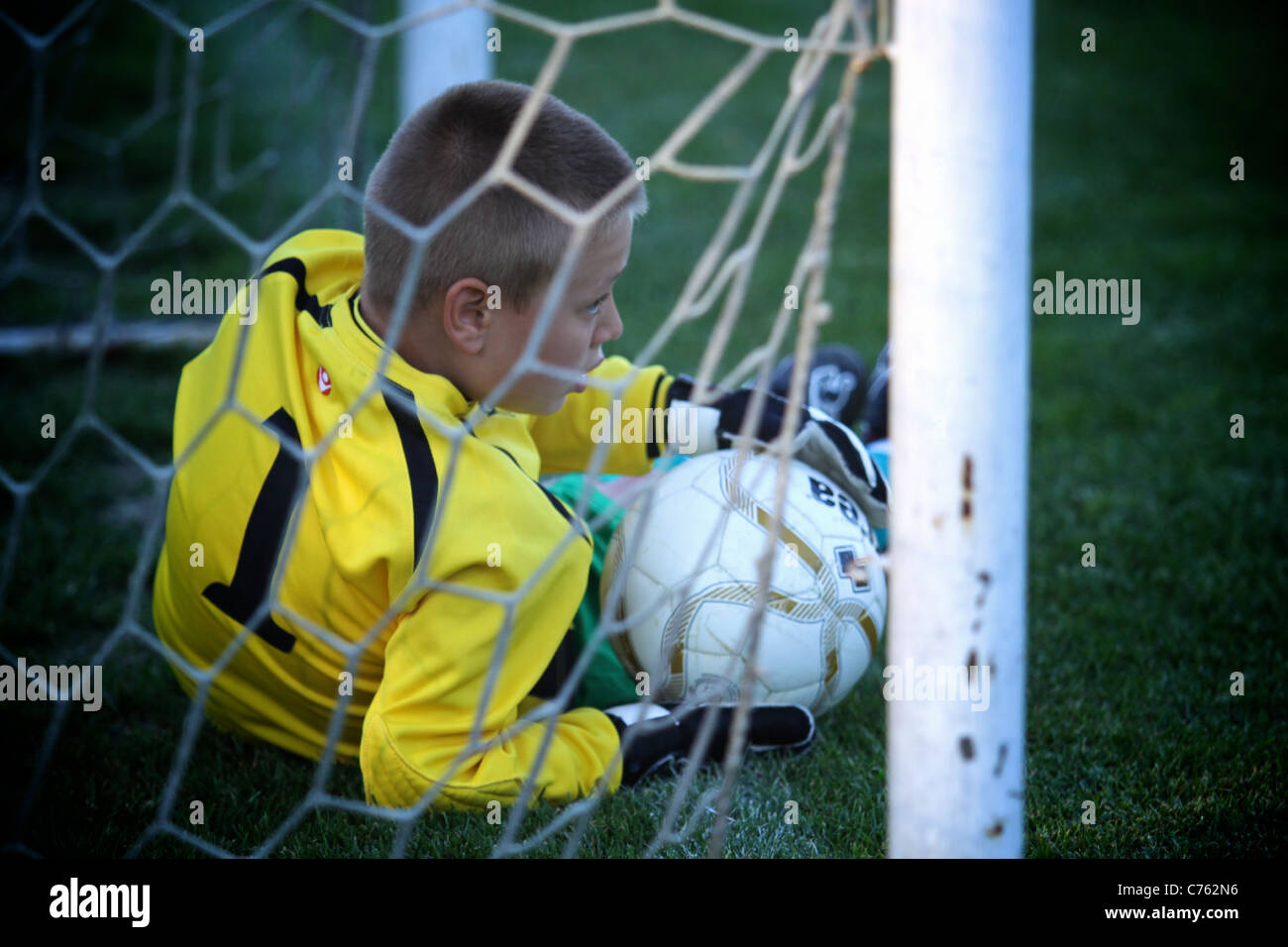 young kid goalkeeper after catch the ball and save the goal from an ...