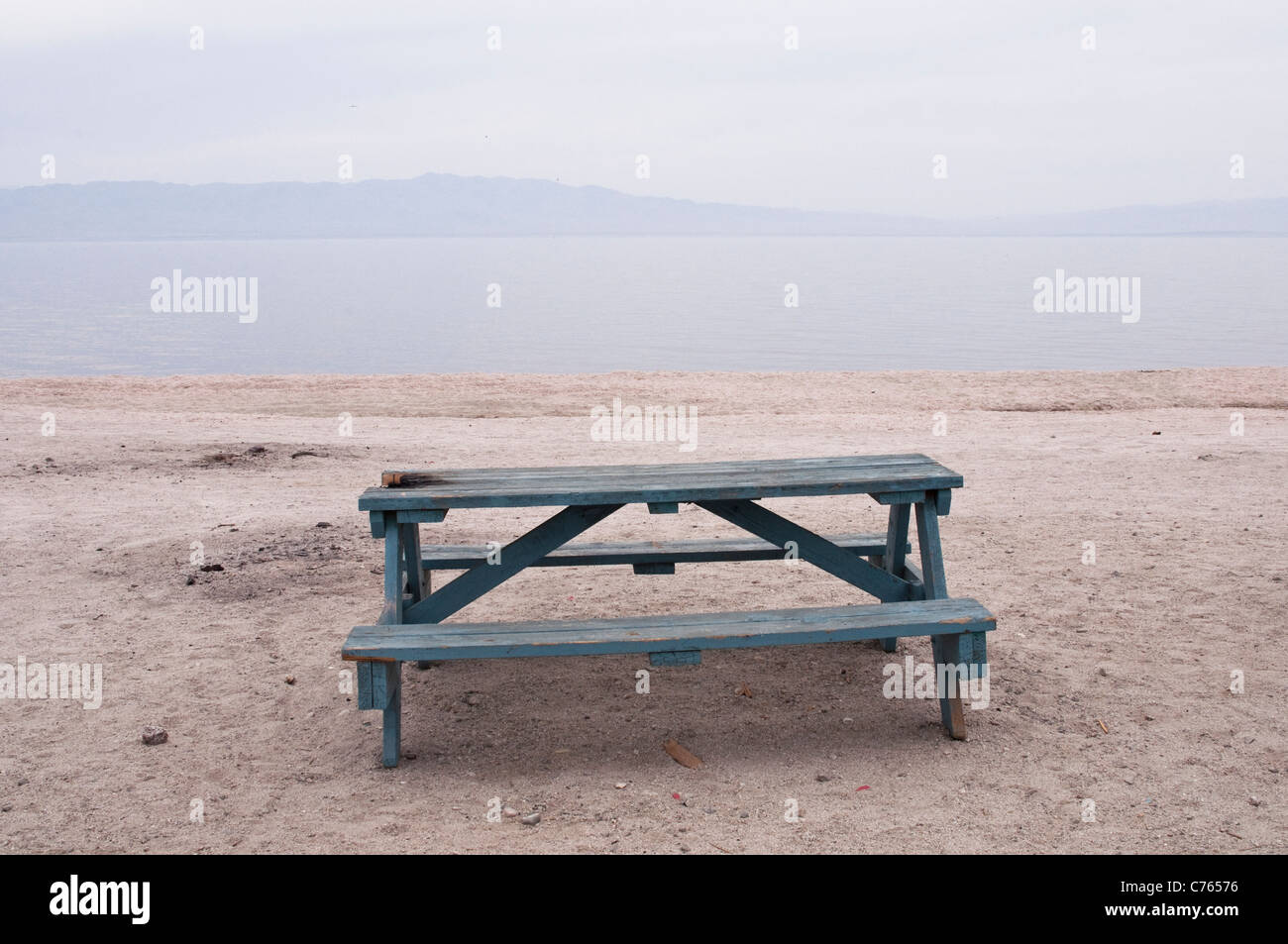 A sloping empty blue wooden picnic table overlooking the Salton Sea ...