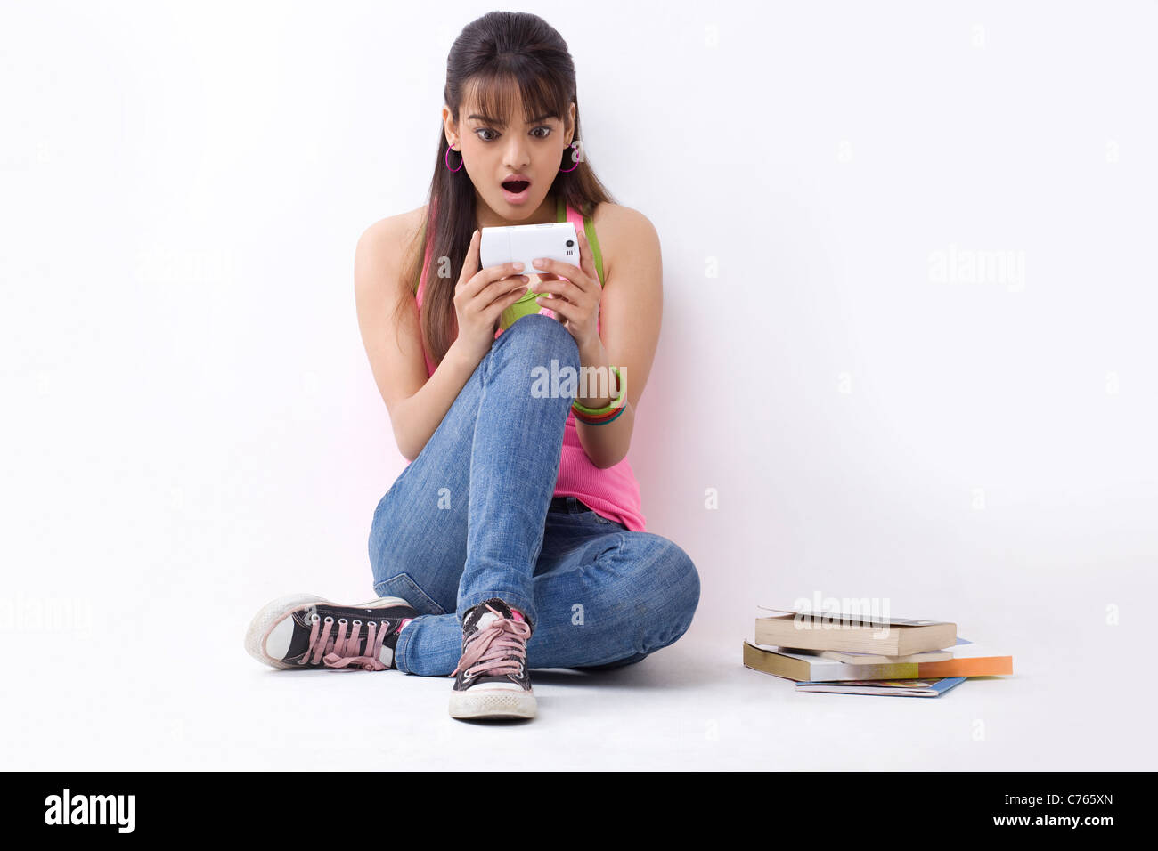 Full length of shocked female college student reading text message ...