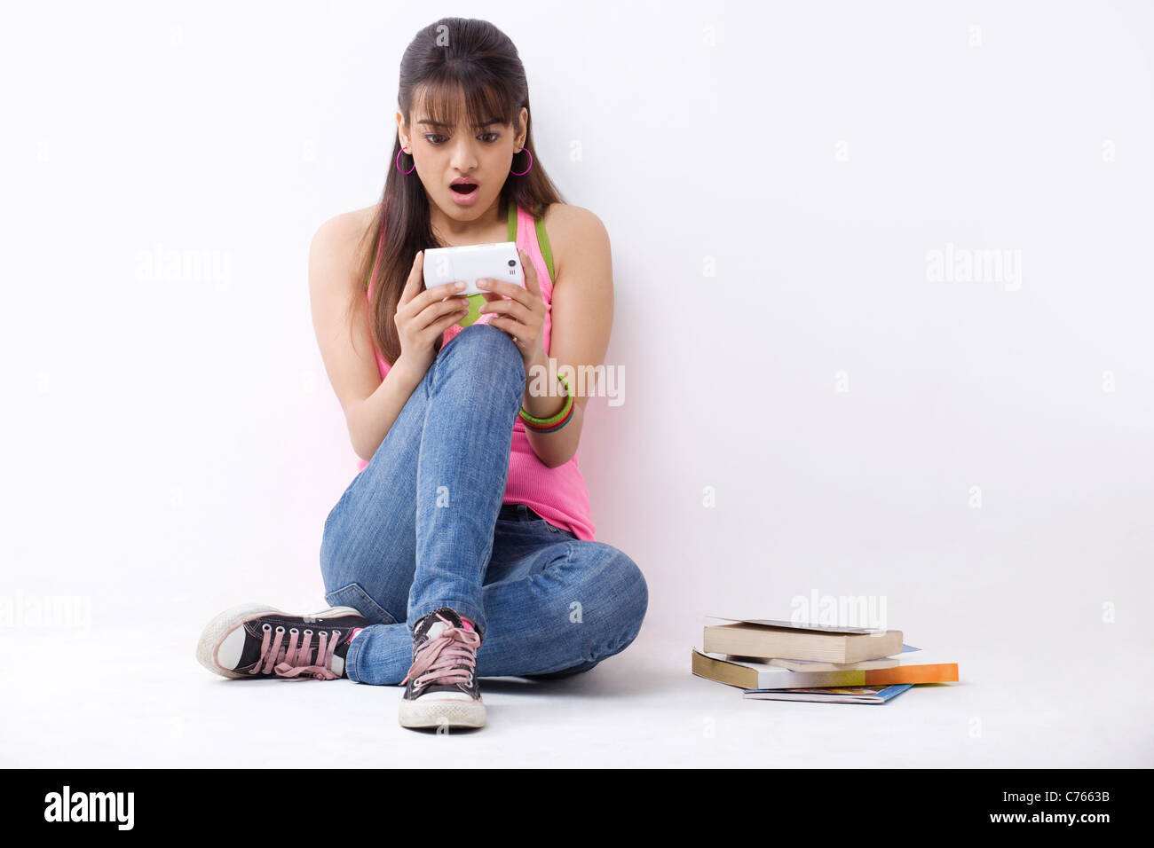 Full length of shocked female university student reading text message ...