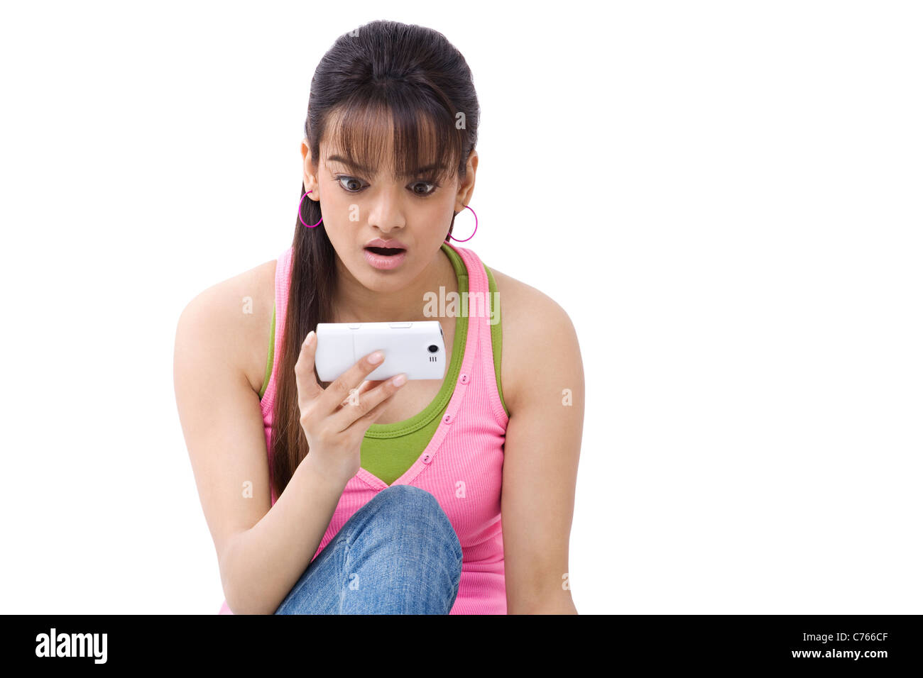 Beautiful young woman looking shocked while reading text message Stock ...